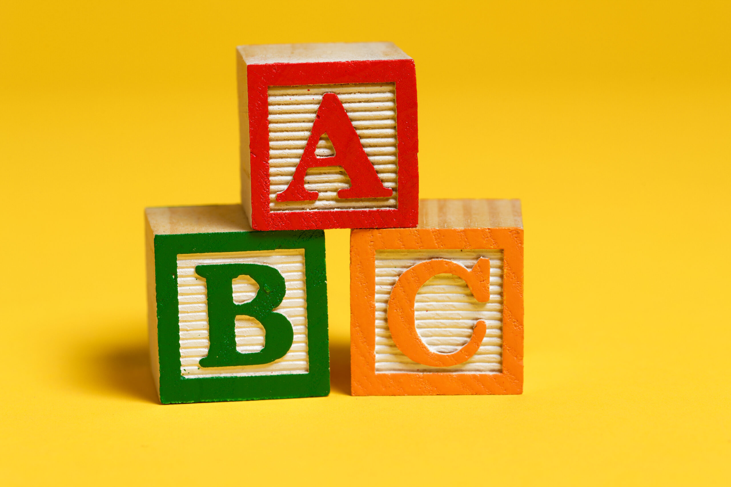 Wooden ABC blocks on yellow background | TRANS.Biz